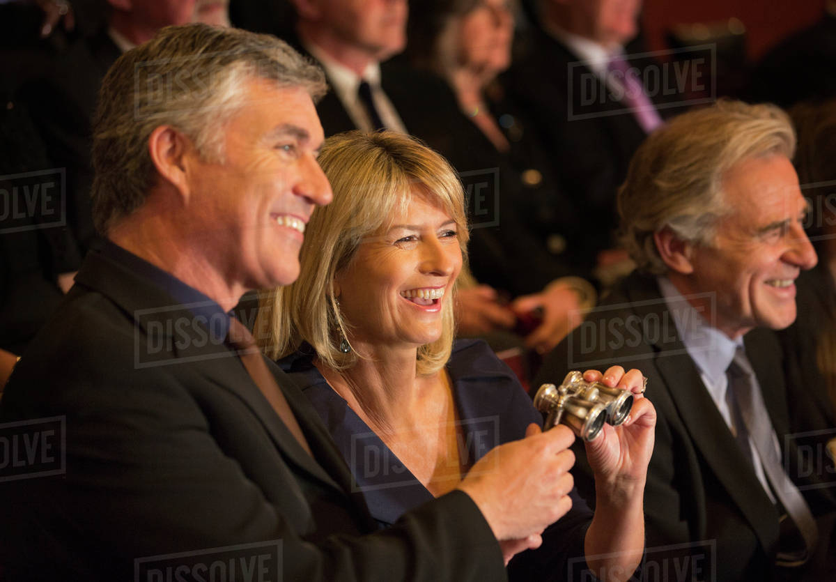 Happy couple holding opera glasses in theater audience - Royalty-free ...