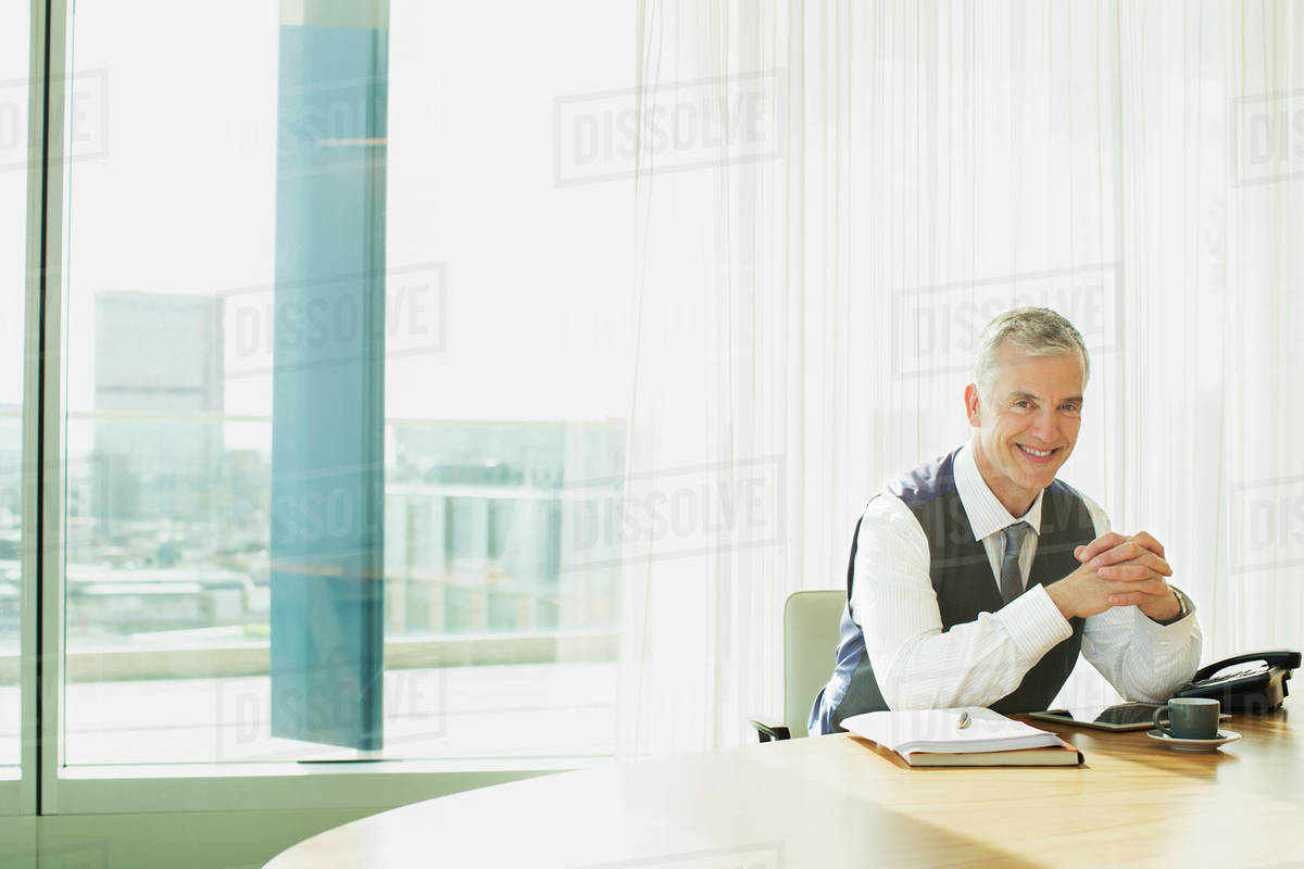 Businessman smiling at desk in office - Royalty-free Stock Photo | Dissolve