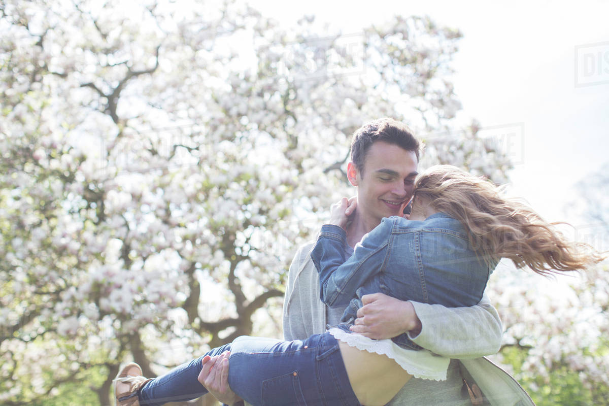Man lifting woman under tree with white blossoms - Royalty-free Stock ...