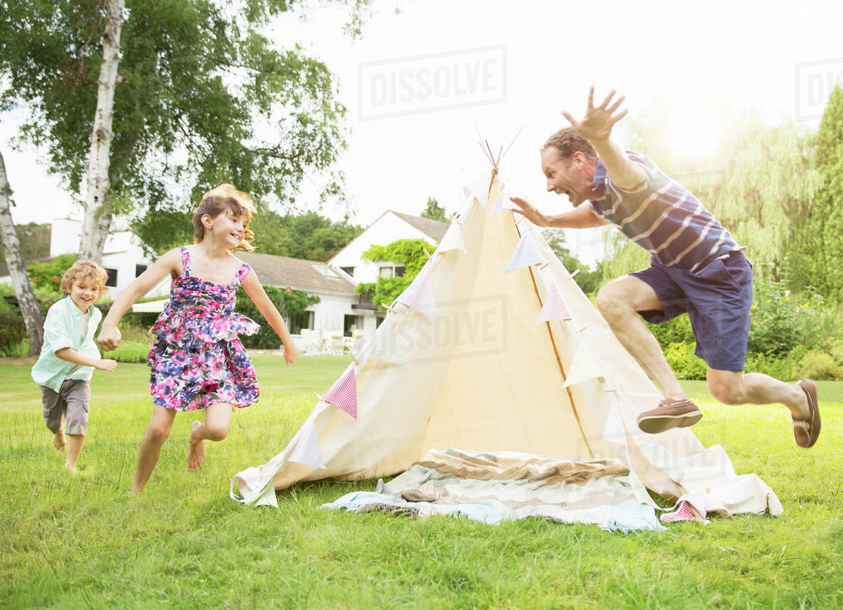 Father chasing children around teepee in backyard - Royalty-free Stock ...