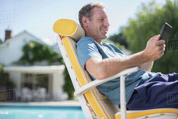 Man reading in lounge chair at poolside - Royalty-free Stock Photo ...