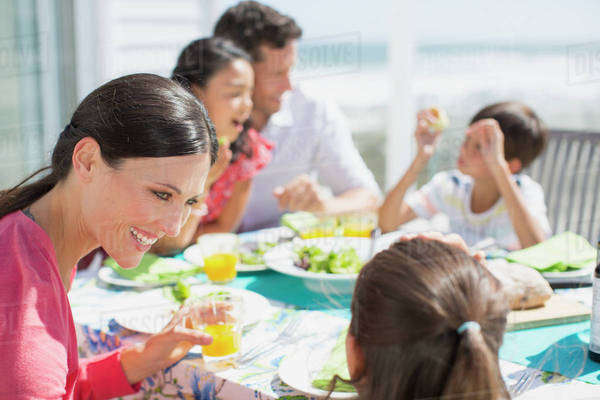 Family eating lunch at table on sunny patio - Royalty-free Stock Photo ...