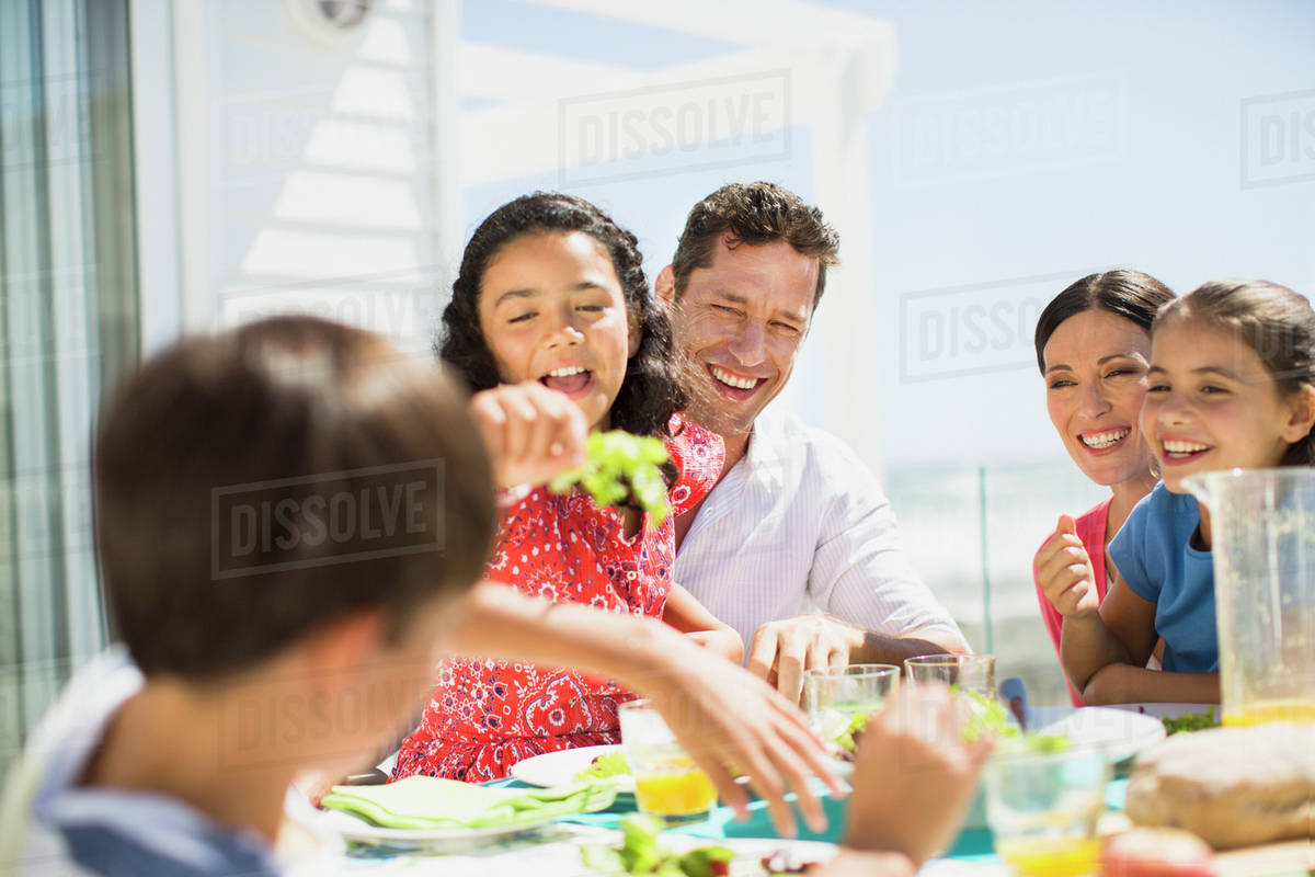 Family eating lunch at table on sunny patio - Stock Photo - Dissolve