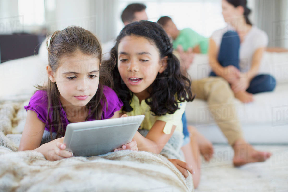 Girls using digital tablet on sofa in living room - Royalty-free Stock ...