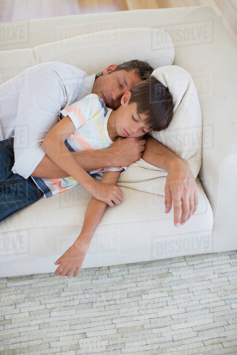 Father and son napping on sofa in living room - Royalty-free Stock ...