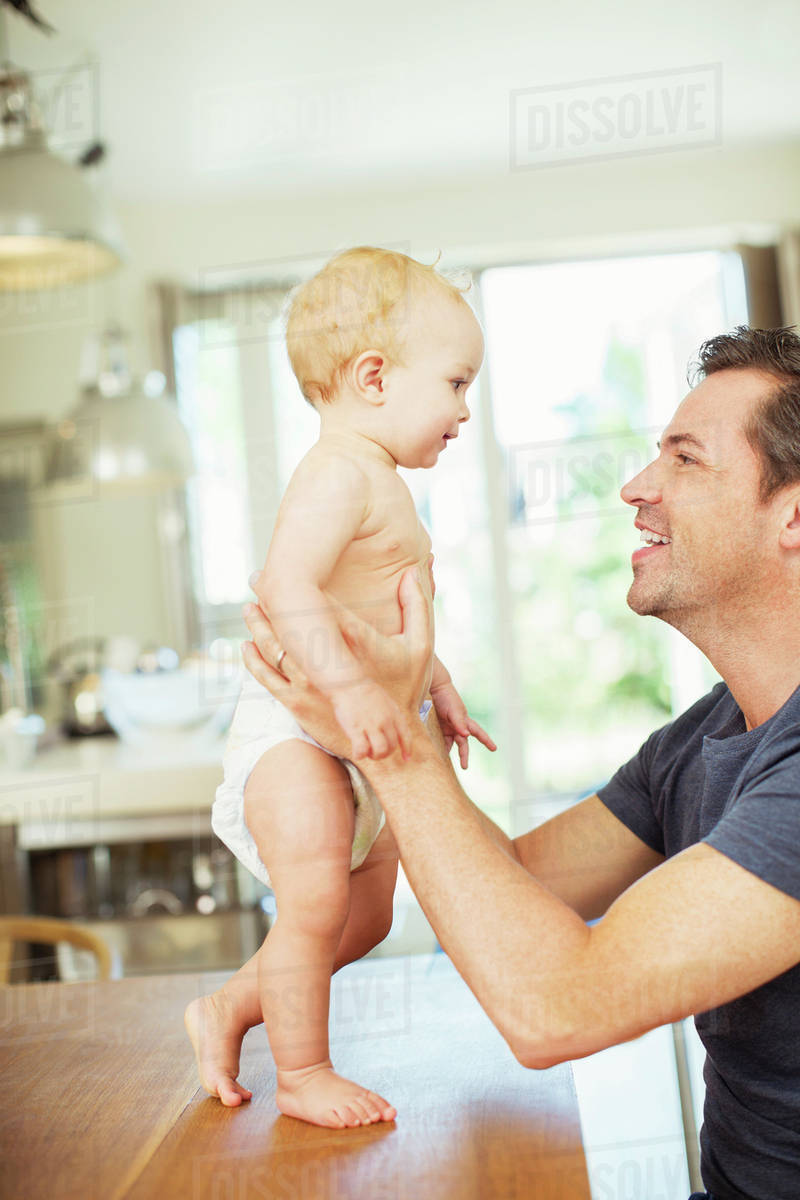 Father helping baby walk on table - Royalty-free Stock Photo | Dissolve