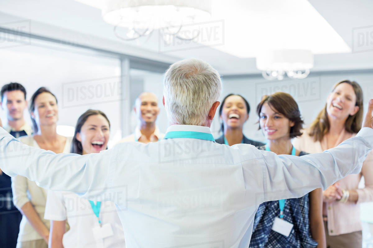 Businessman greeting enthusiastic colleagues in office - Stock Photo ...