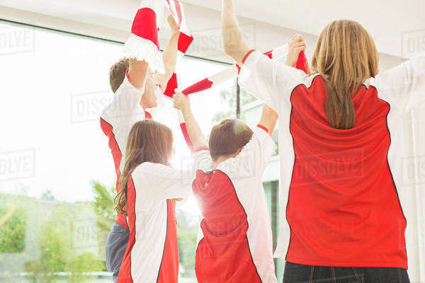 Family in sports jerseys cheering together - Stock Photo - Dissolve