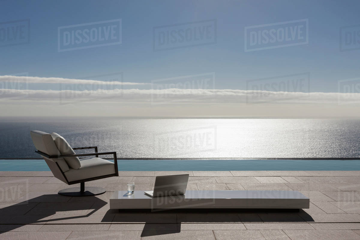 Modern patio and infinity pool overlooking ocean - Royalty-free Stock Photo | Dissolve