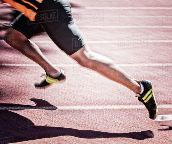 Sprinter taking off from starting block on track - Stock Photo - Dissolve