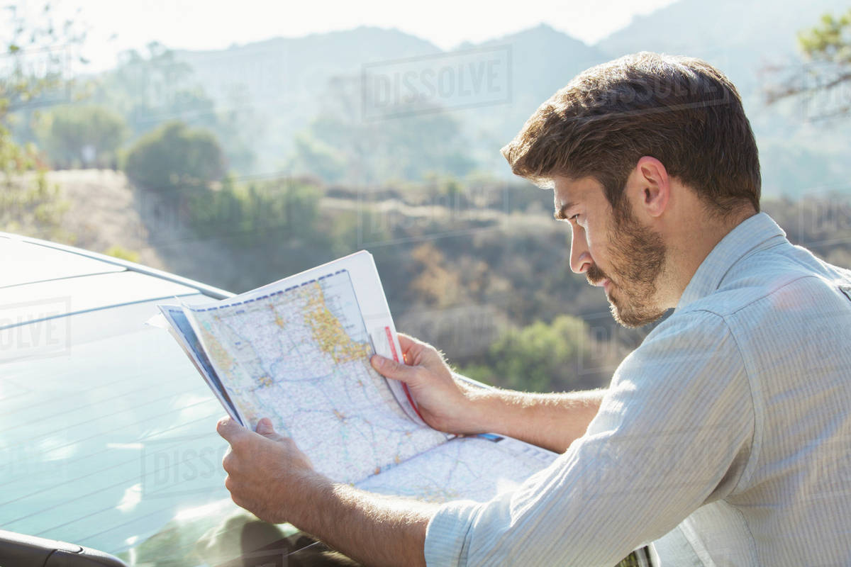 Man looking at map outside car - Royalty-free Stock Photo | Dissolve