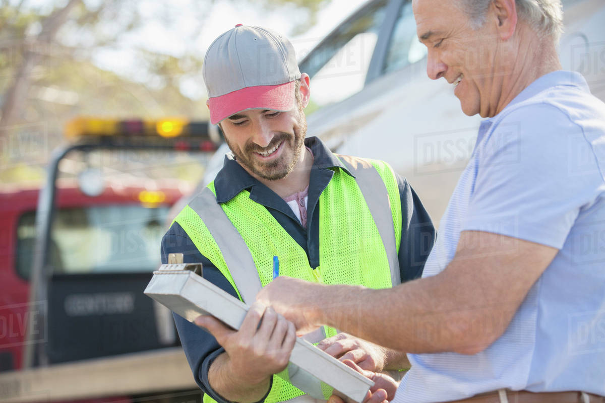 Man signing paperwork for roadside mechanic - Royalty-free Stock Photo ...