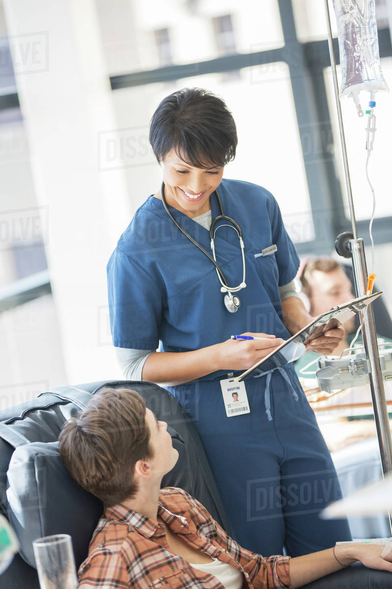 Doctor attending patient receiving intravenous infusion in hospital ...