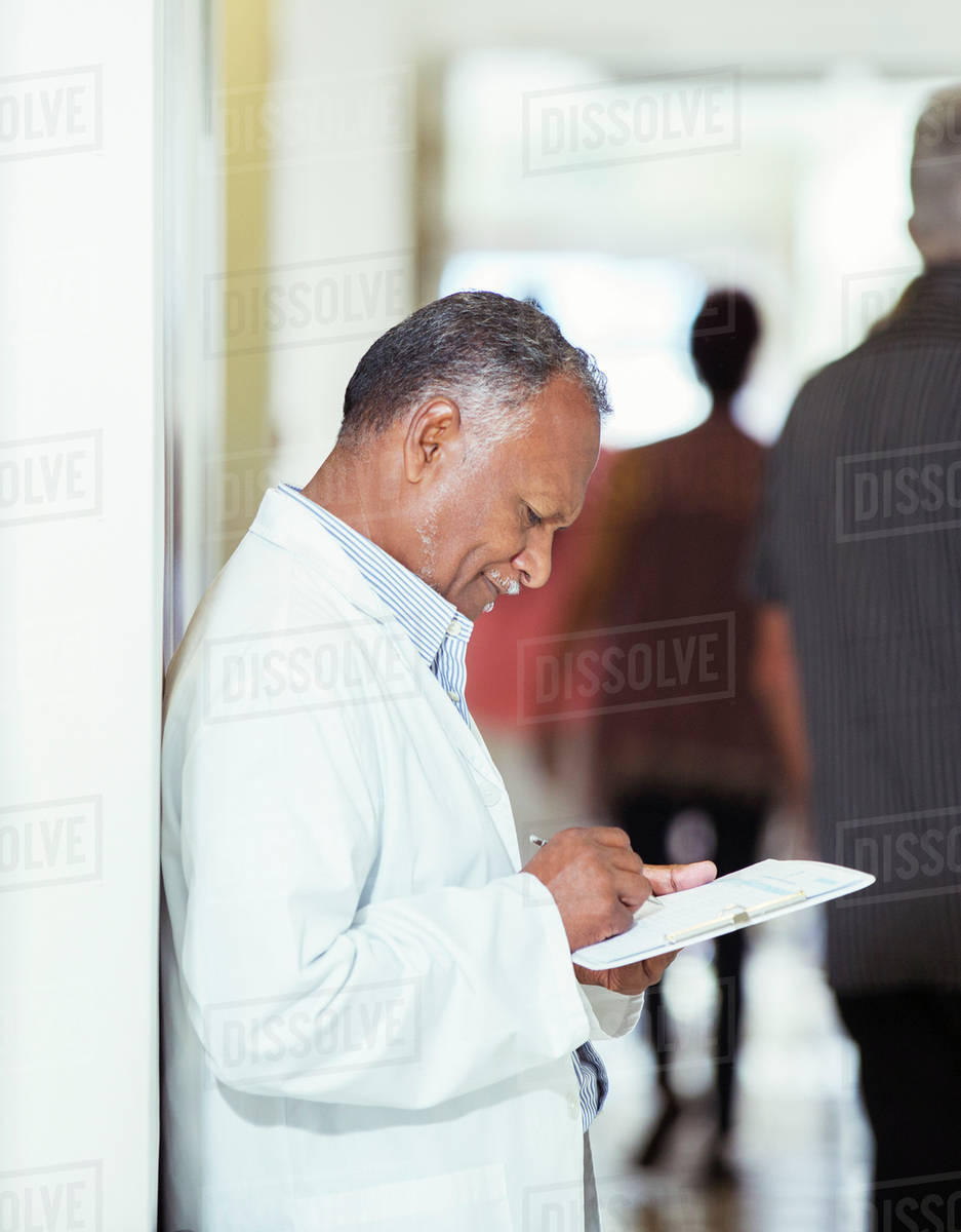 Doctor writing on medical chart in hospital - Stock Photo - Dissolve