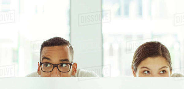 People peeking over cubicle in office - Stock Photo - Dissolve