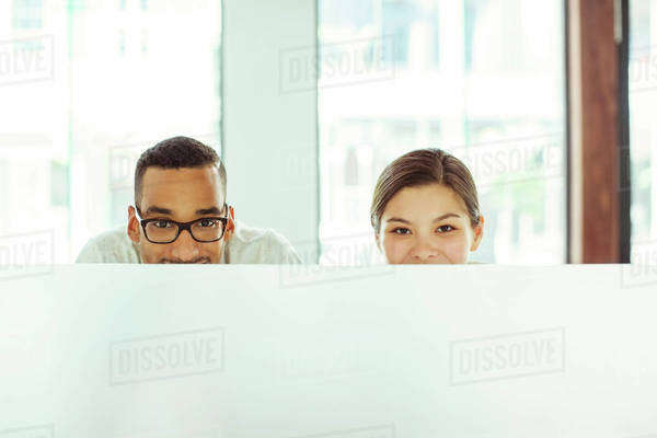 People peering over cubicle in office - Stock Photo - Dissolve
