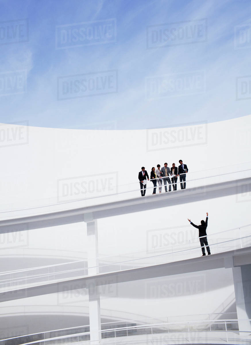 Business people looking down at businessman with arms raised on ...