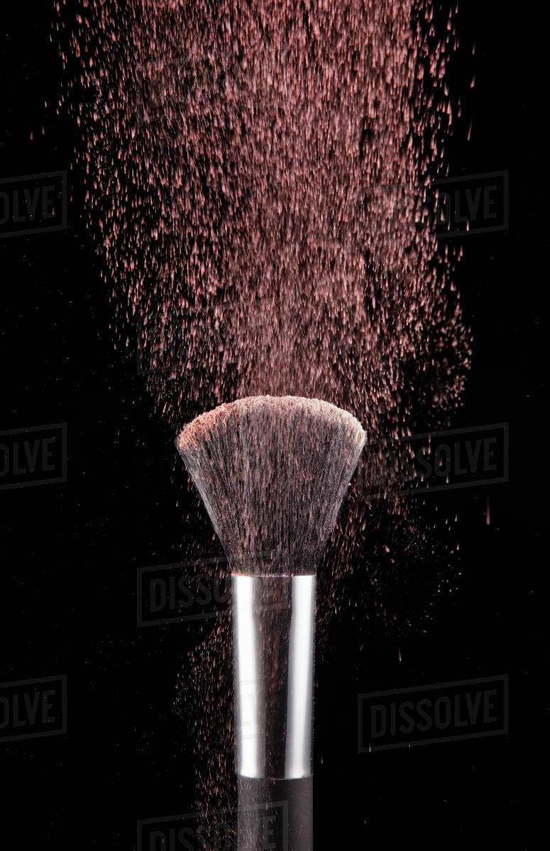 Blush powder blowing from makeup brush - Stock Photo - Dissolve