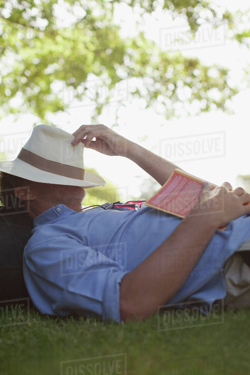Man napping in grass with book and hat covering face - Royalty-free ...
