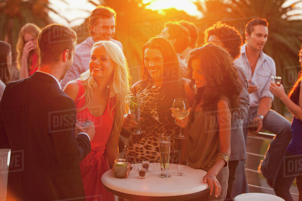 Smiling friends drinking cocktails on sunny balcony - Stock Photo ...