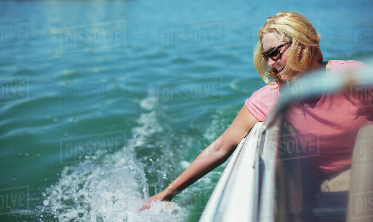 Older woman trailing hand in water from boat - Royalty-free Stock Photo ...
