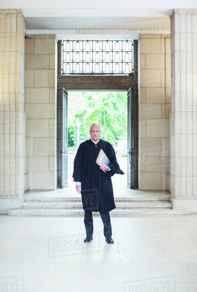 Judge standing in front of doors to courthouse - Stock Photo - Dissolve