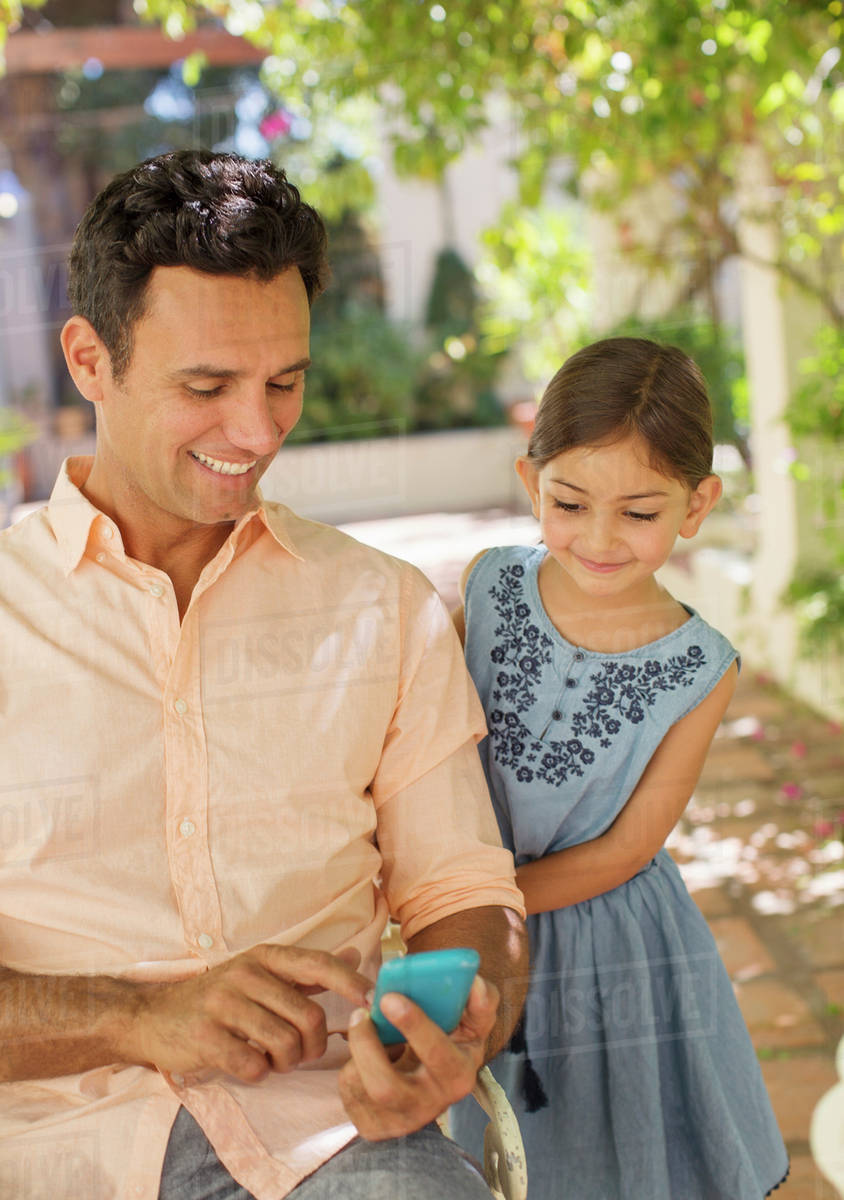 Father and daughter looking at cell phone - Stock Photo - Dissolve