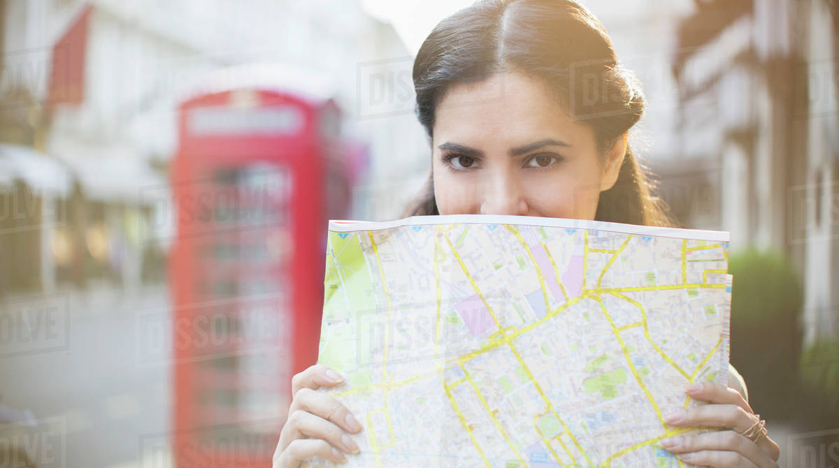 Woman holding map on city street - Royalty-free Stock Photo | Dissolve