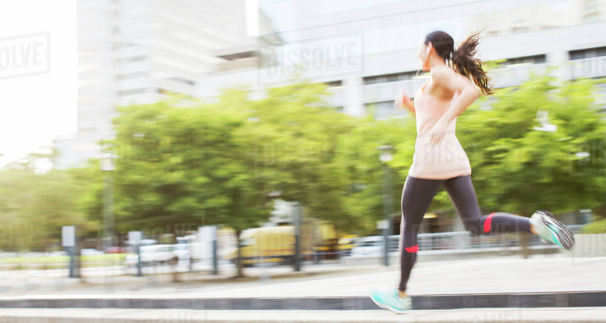 Woman running through city streets - Stock Photo - Dissolve