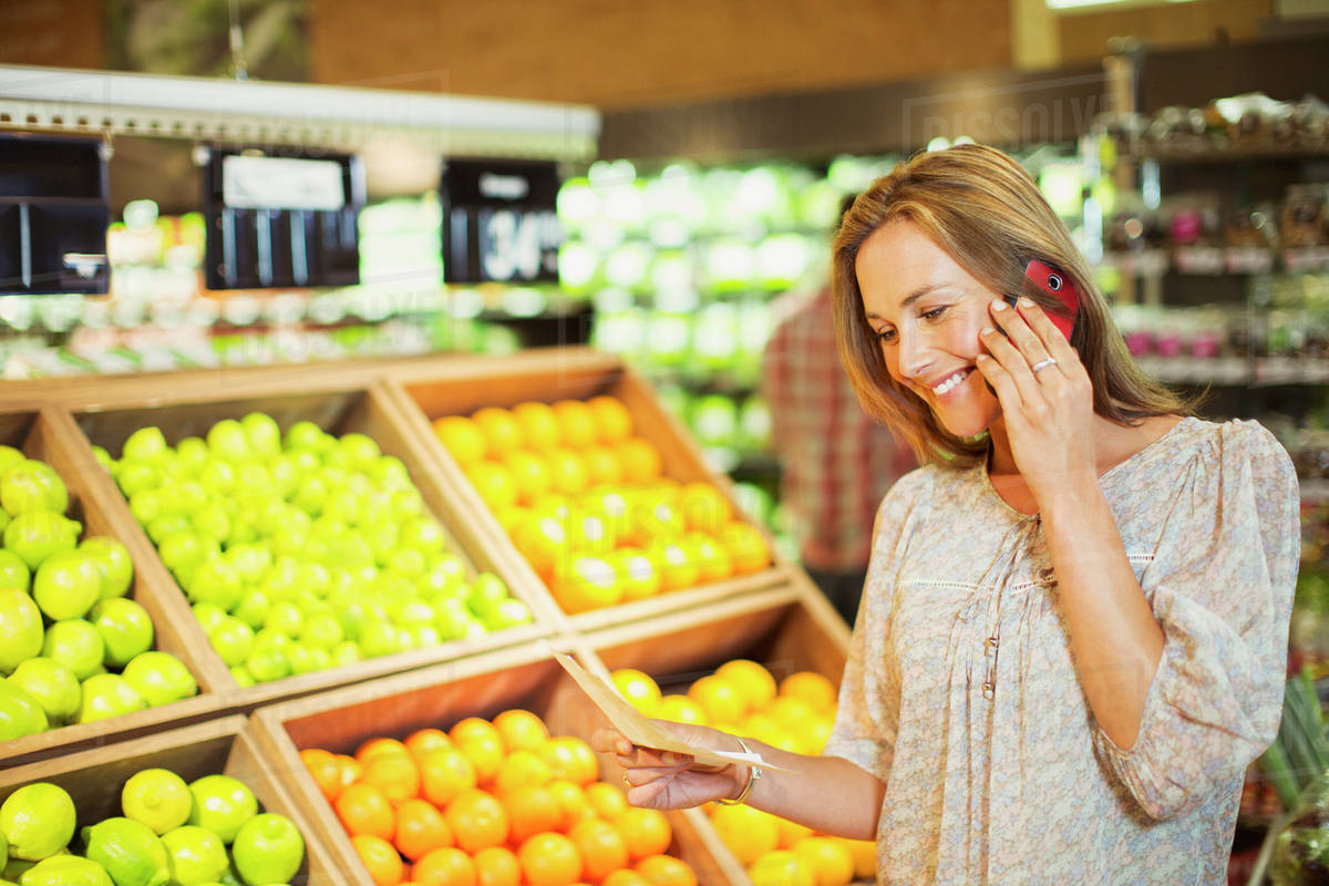 Woman talking on cell phone while shopping in grocery store - Stock ...