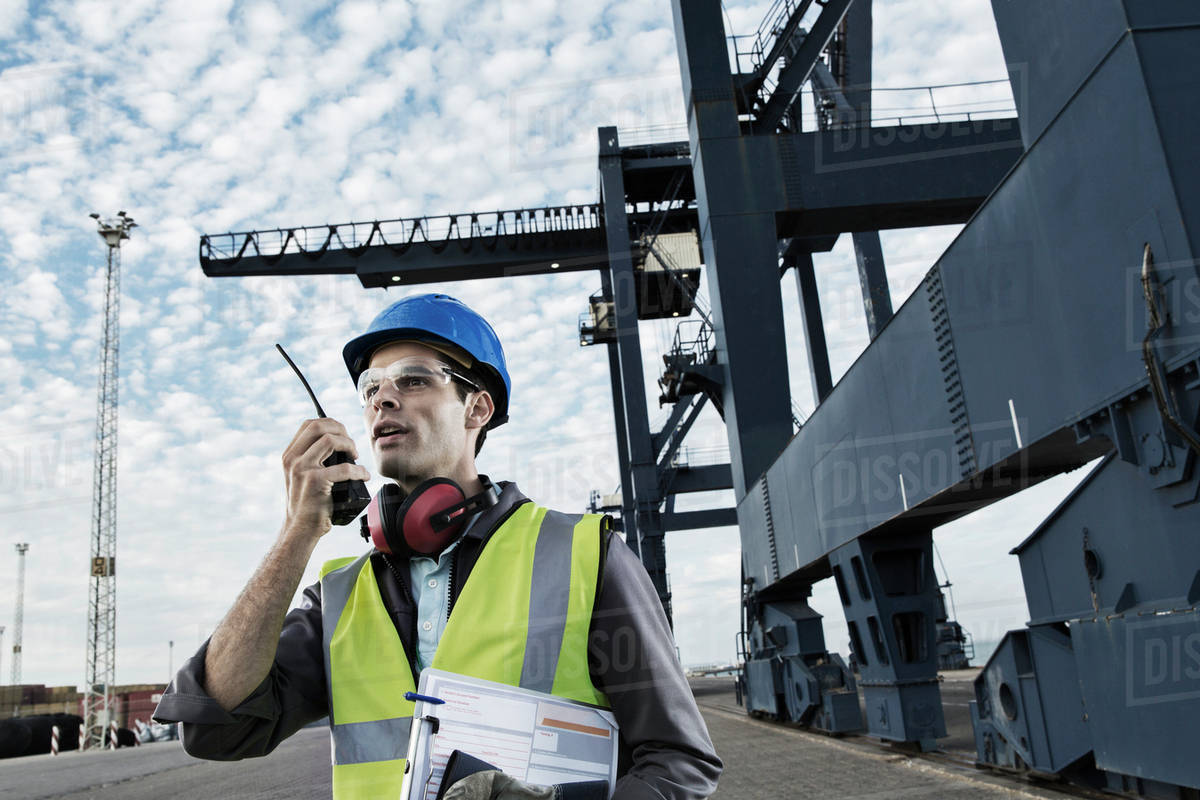 Worker using walkie-talkie near crane - Royalty-free Stock Photo | Dissolve