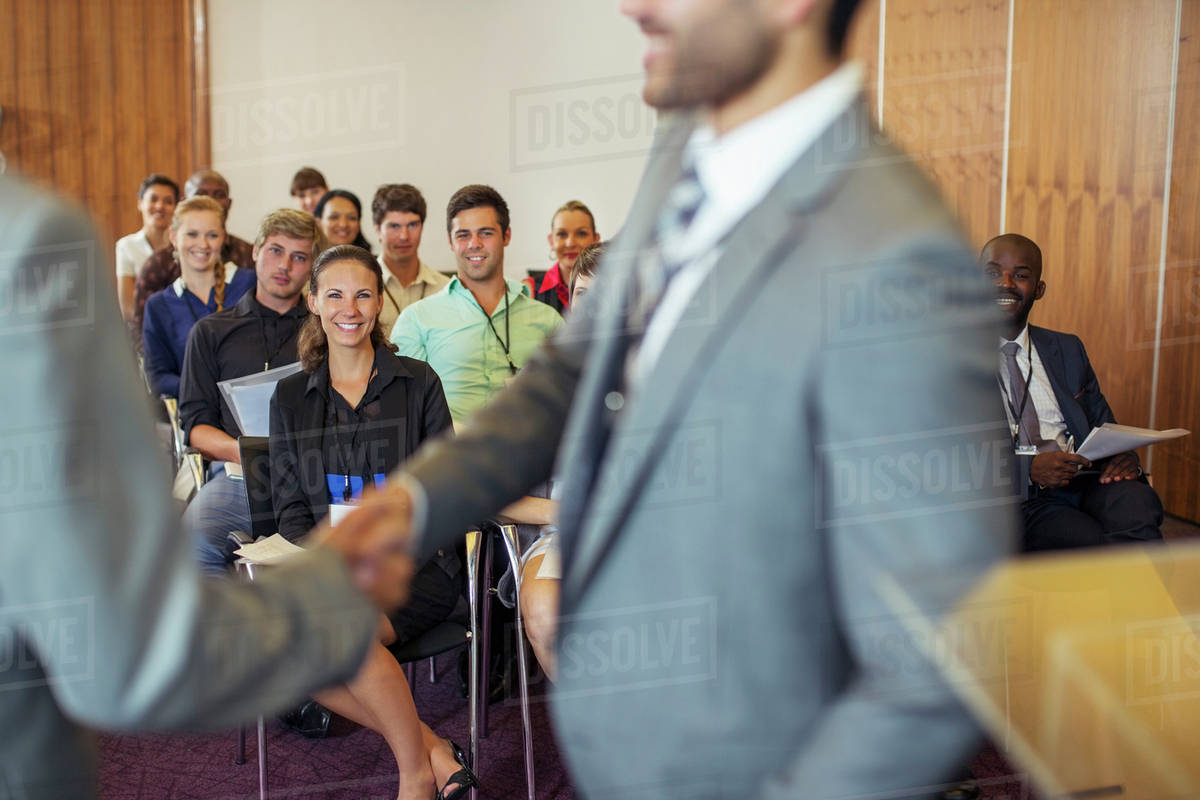 Two businessmen shaking hands during conference in conference room ...