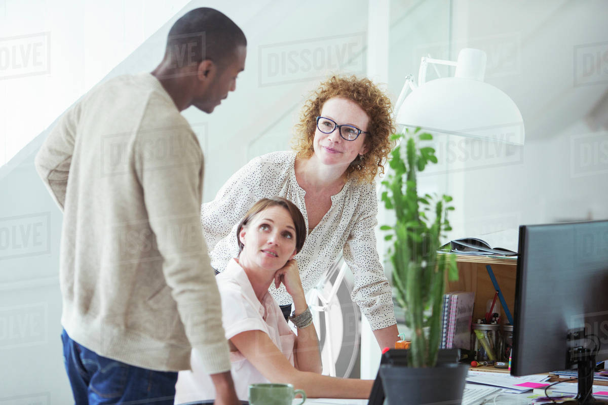 Office workers talking at desk - Royalty-free Stock Photo | Dissolve