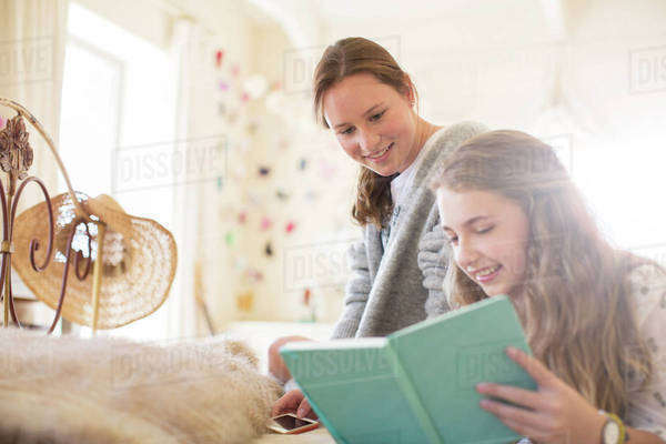 Two teenage girls reading book together on bed - Royalty-free Stock ...