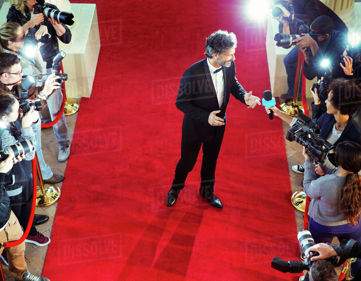 Celebrity on red carpet being interviewed and photographed by paparazzi ...