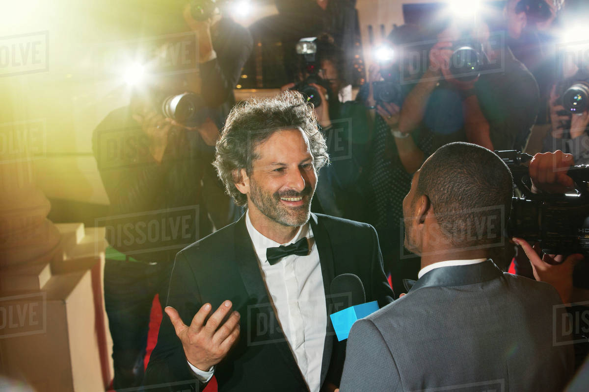 Celebrity being interviewed and photographed by paparazzi photographers ...