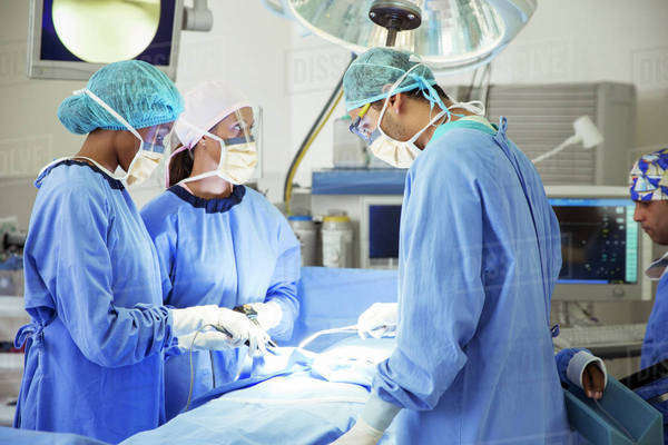 Surgeons performing surgery in operating room - Stock Photo - Dissolve