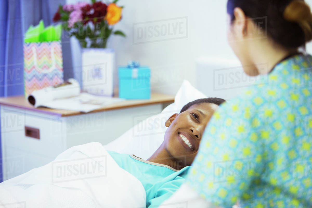 Smiling patient in hospital bed smiling at nurse - Stock Photo - Dissolve