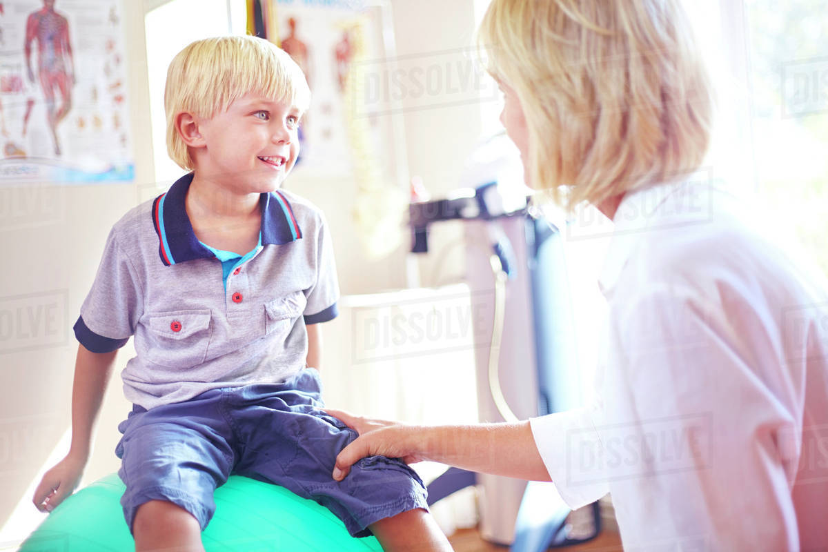 Physical therapist talking to boy on fitness ball - Royalty-free Stock ...