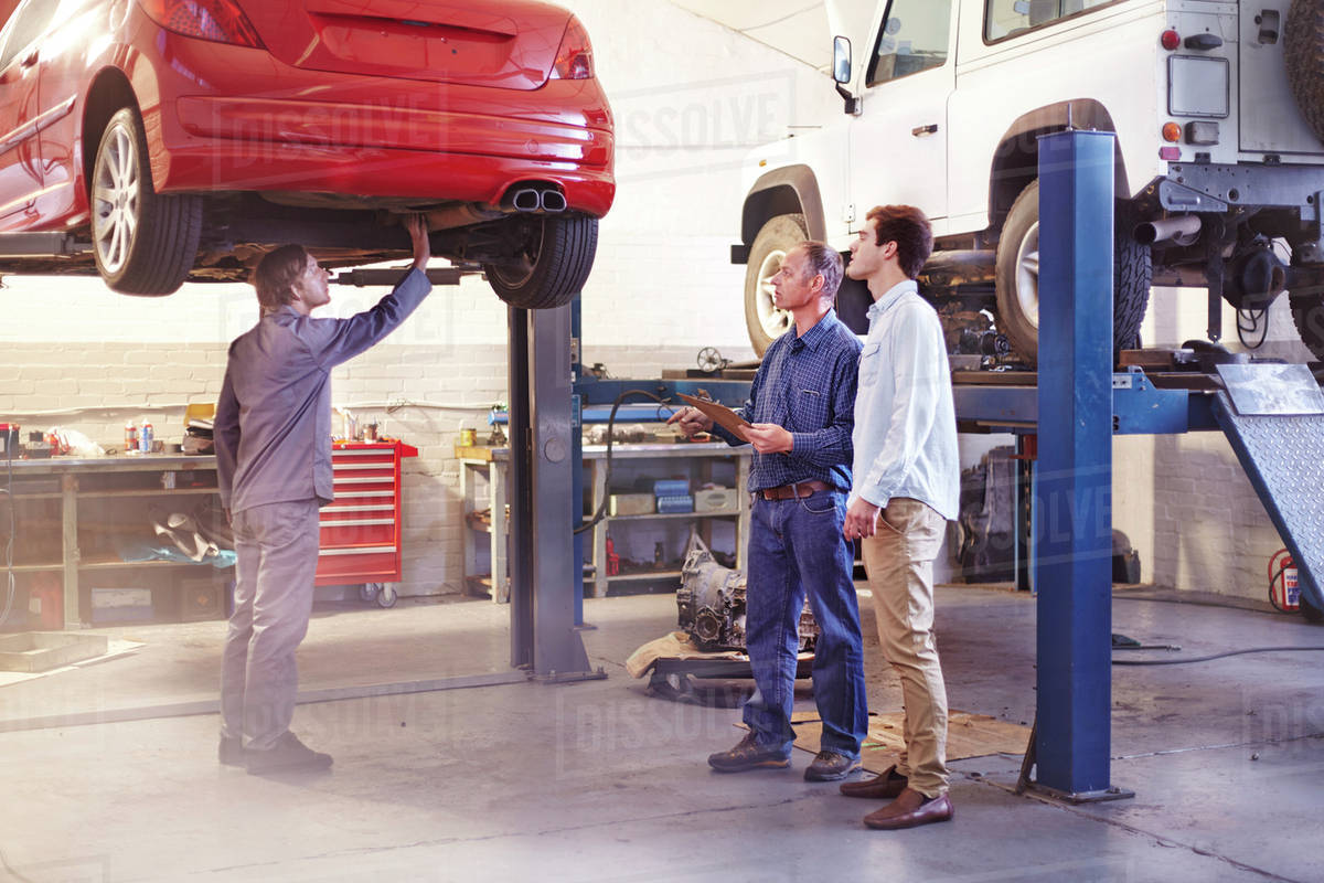 Mechanic talking to customer in auto repair shop - Stock Photo - Dissolve