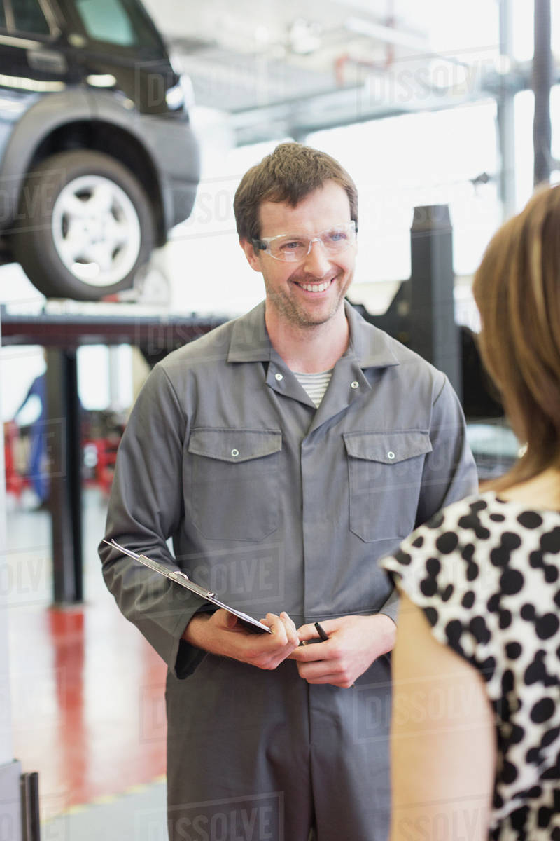 Mechanic with clipboard talking to customer in auto repair shop - Stock ...