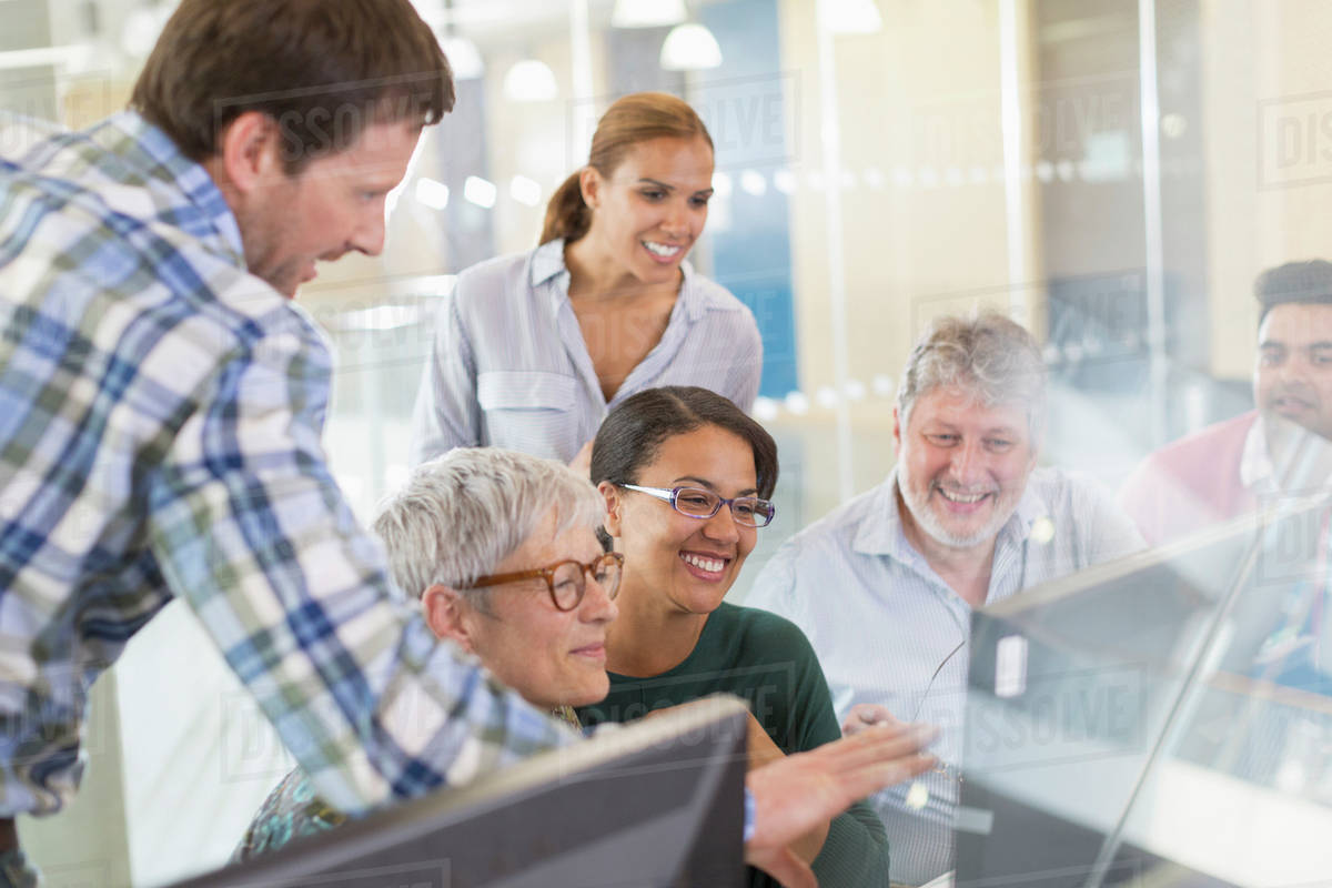 Smiling students at computer in adult education classroom - Royalty ...