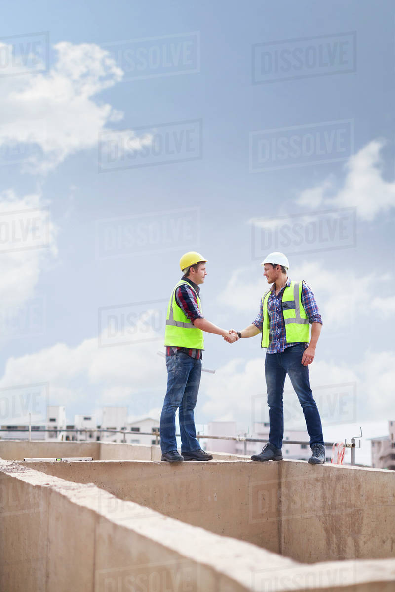 Construction workers handshaking at highrise construction site - Stock ...