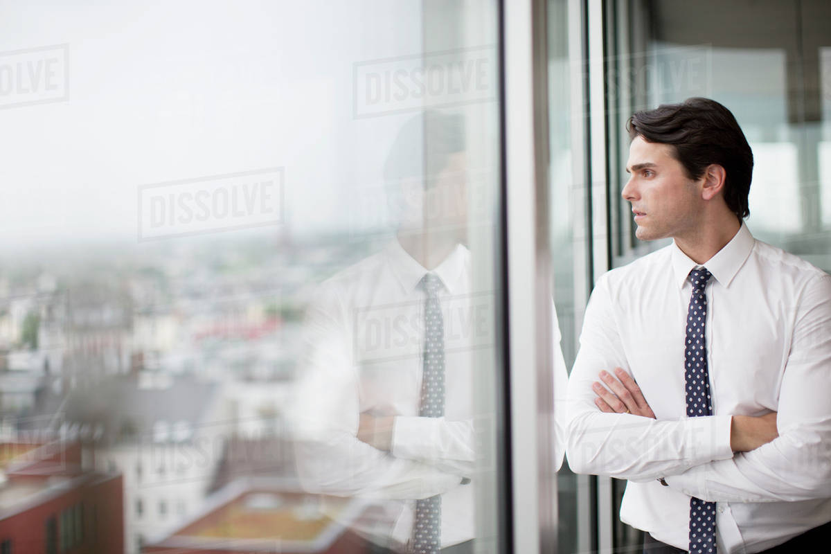 Businessman looking out office window - Stock Photo - Dissolve