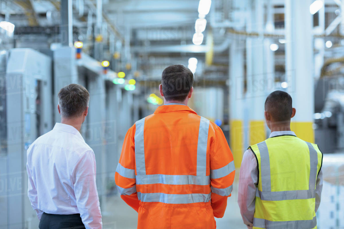 Workers and supervisor standing in factory corridor - Royalty-free ...