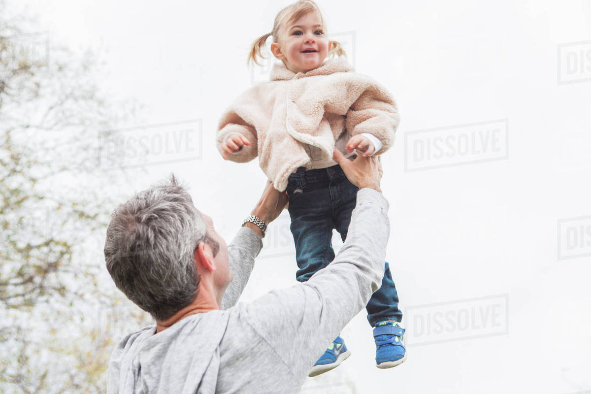 Father lifting toddler daughter overhead - Stock Photo - Dissolve