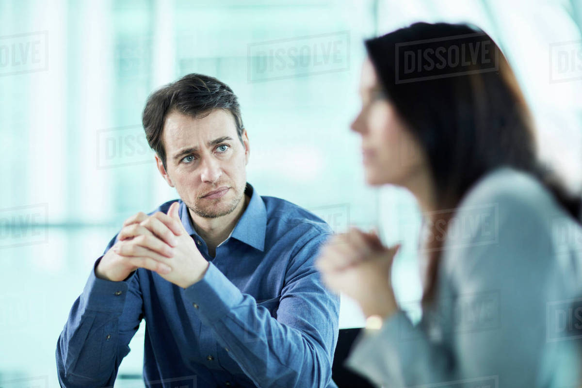 Attentive serious businessman listening to businesswoman in meeting ...