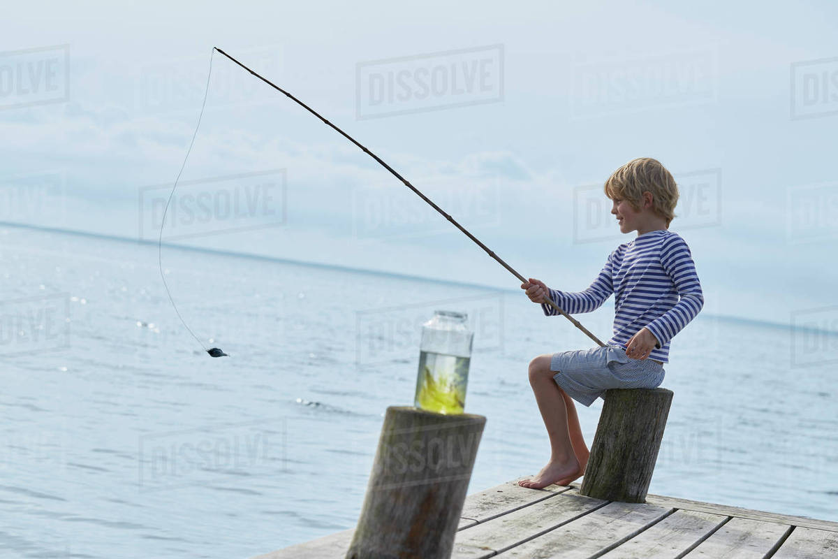 Boy fishing off lakeside dock - Royalty-free Stock Photo | Dissolve