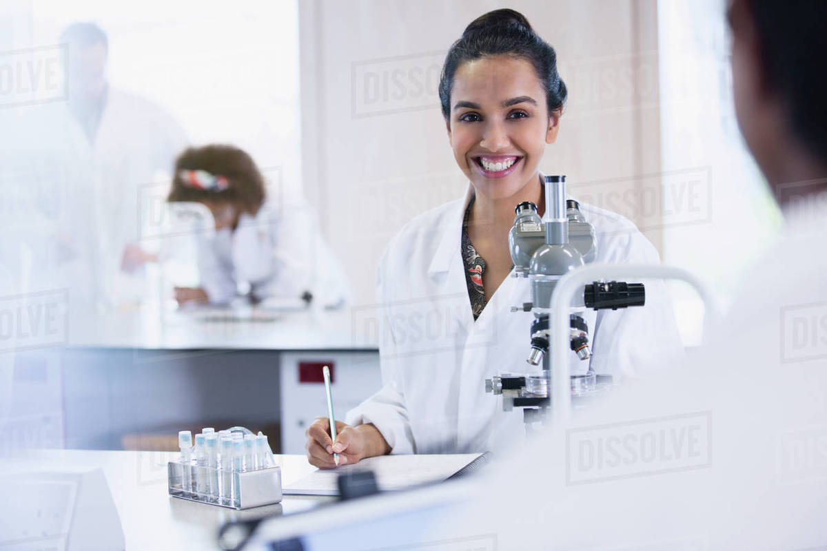 Smiling female college student conducting scientific experiment in ...