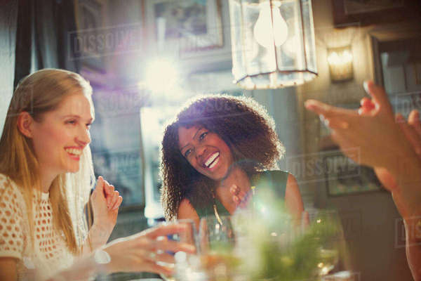 Laughing women friends clapping and dining at restaurant table - Stock ...
